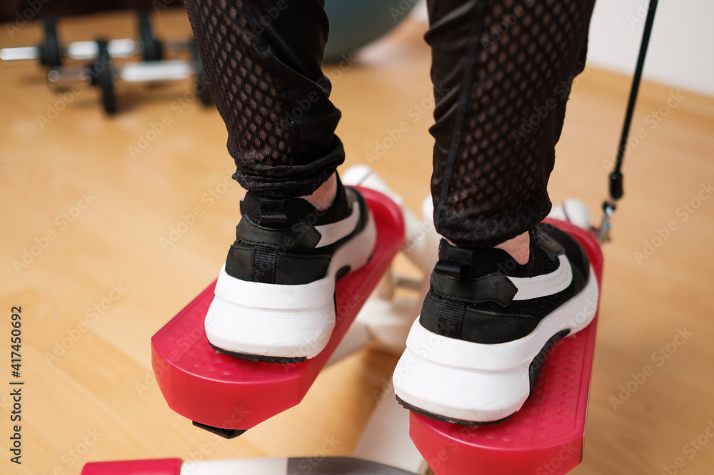Back view on the woman feet in sneakers doing exercising on the twist ...
