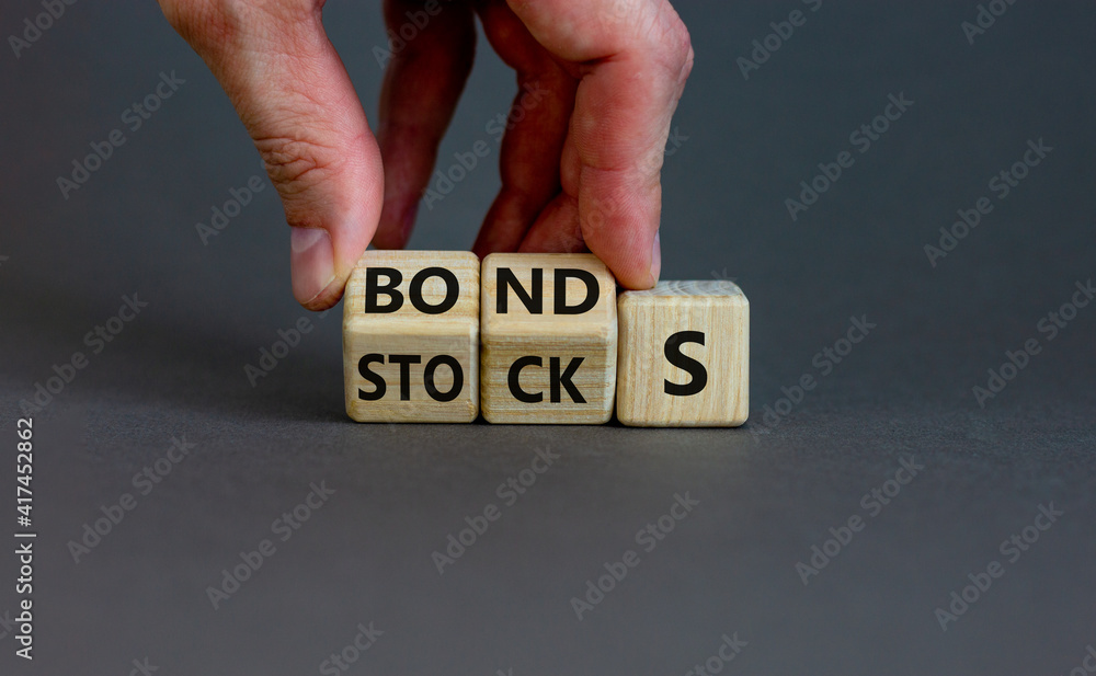 Stocks vs bonds symbol. Businessman turns wooden cubes and changes the ...