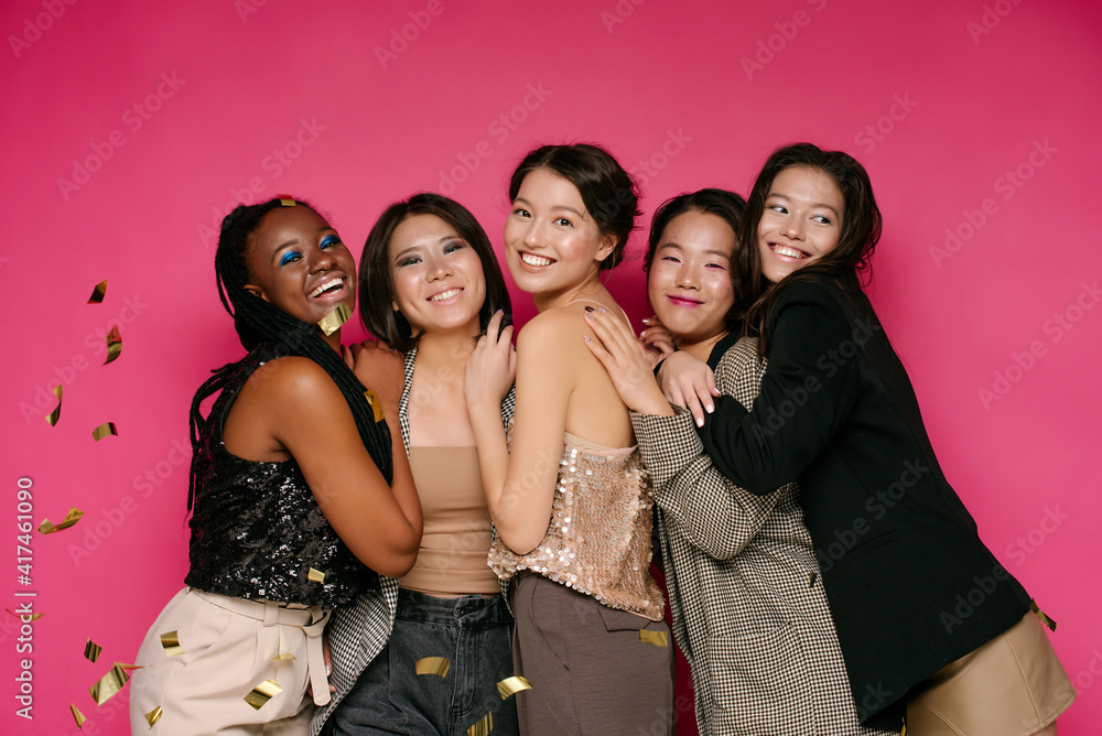 Portrait of five beautiful women with gold confetti falling around them ...