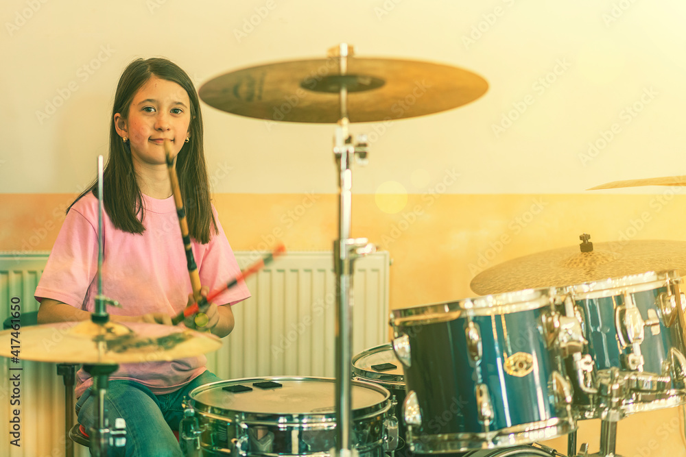 Happy girl in music therapy by playing drum kit on music room ...