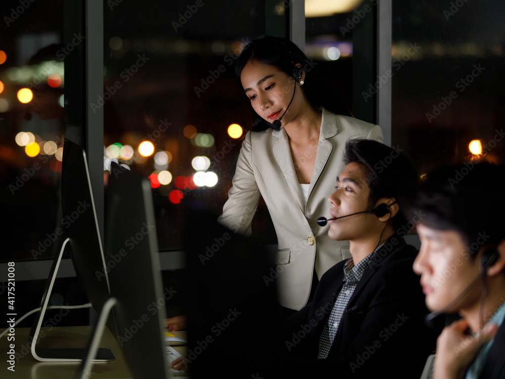 Asian team call center officer wearing headphone looking at computer ...
