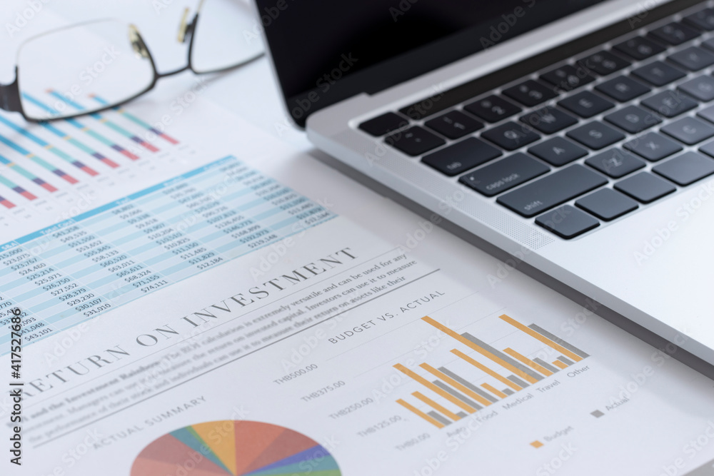 Closeup of laptop or notebook computer and financial reports with ...