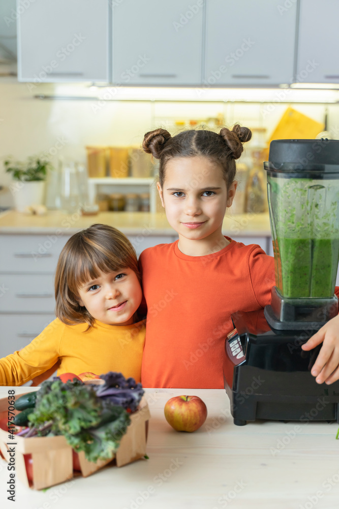 Children open and pour green smoothies from blender in the kitchen ...