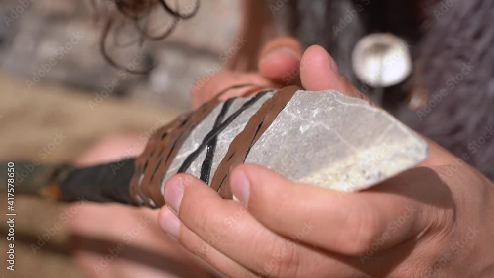 Caveman makes hunting tool of wooden stick, sharpened stone and leather ...
