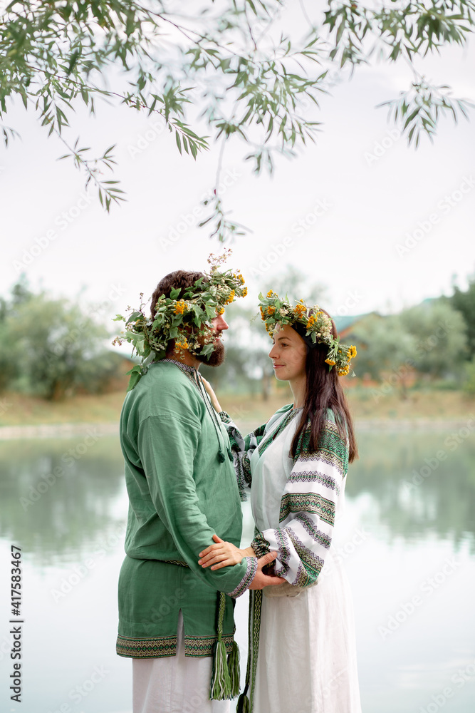 Foto de Beautiful slavonic couple with flower crowns in white and green ...