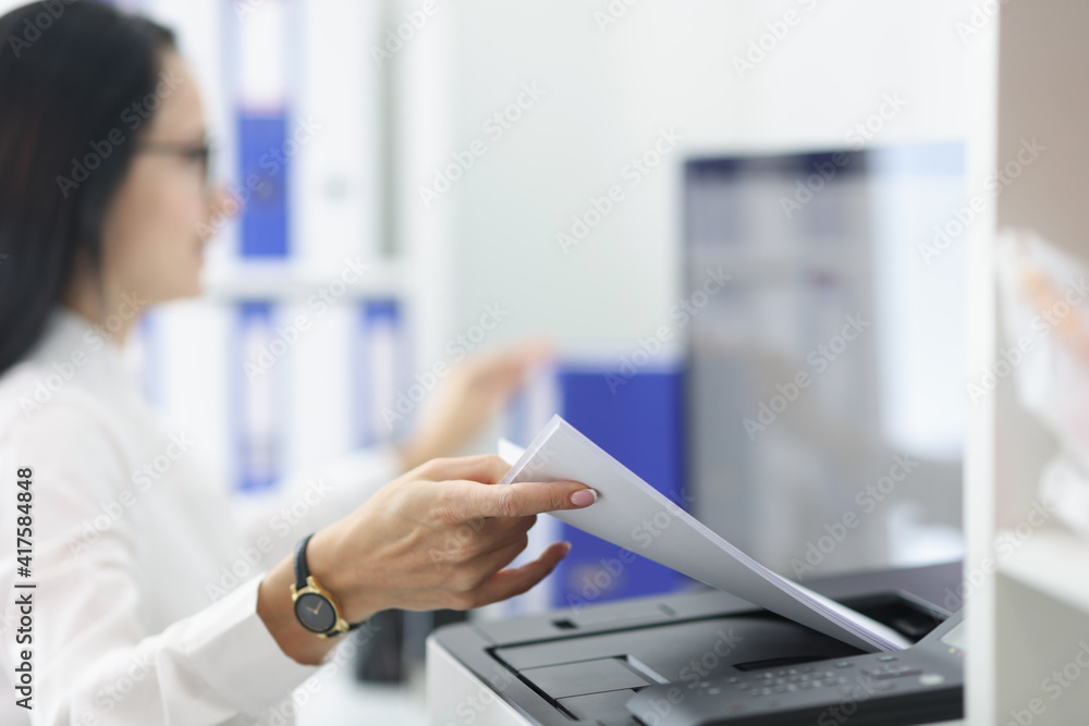 Young woman pulling paper out of printer closeup. Replacement of ...