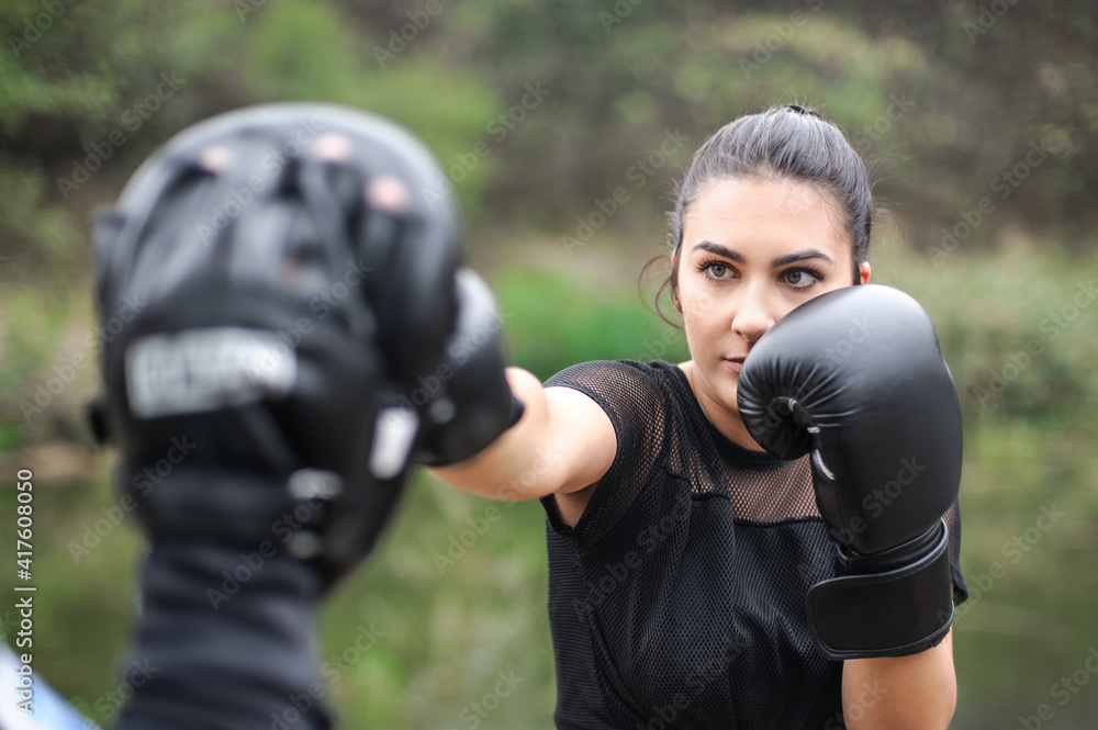 Sporty girl doing boxing exercises with trainer. Fitness outdoors ...