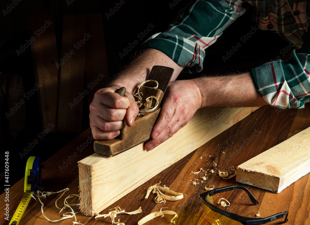 Foto de Woodworker using a hand plane to clean up a wooden board. Hands ...