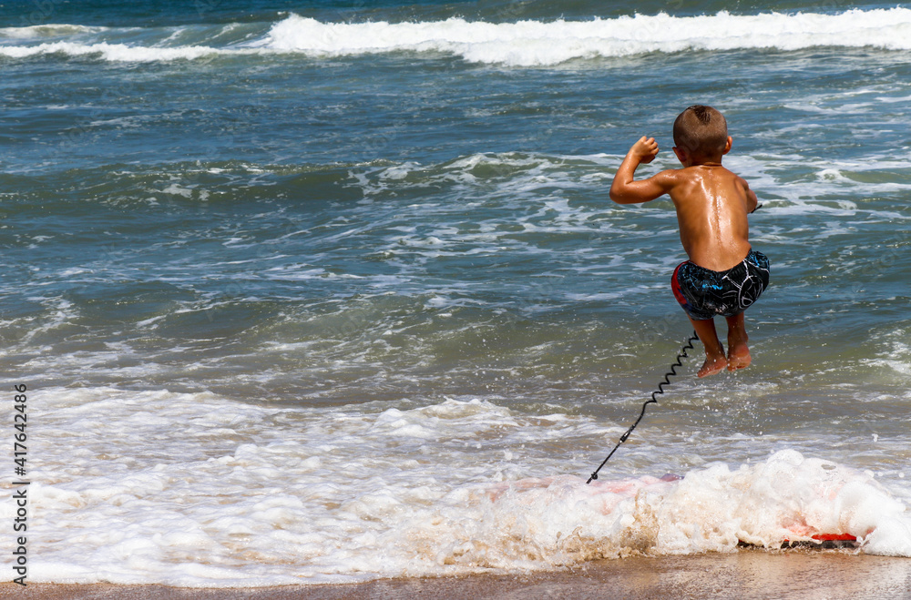 Adventurous Young boy catching air before catching a wave with his ...