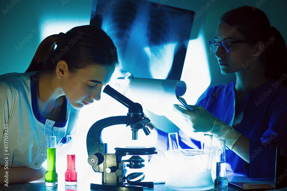 Student girl looking in a microscope, science laboratory concept. Two ...