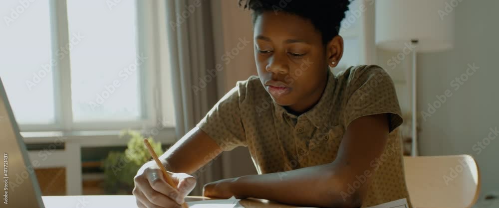 African American Black kid boy doing his homework at home. Distance ...