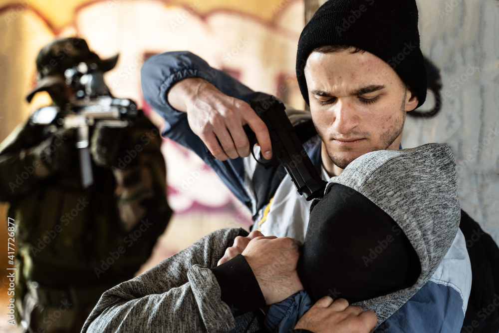 Front view on criminal or terrorist holding unknown hostage pointing ...