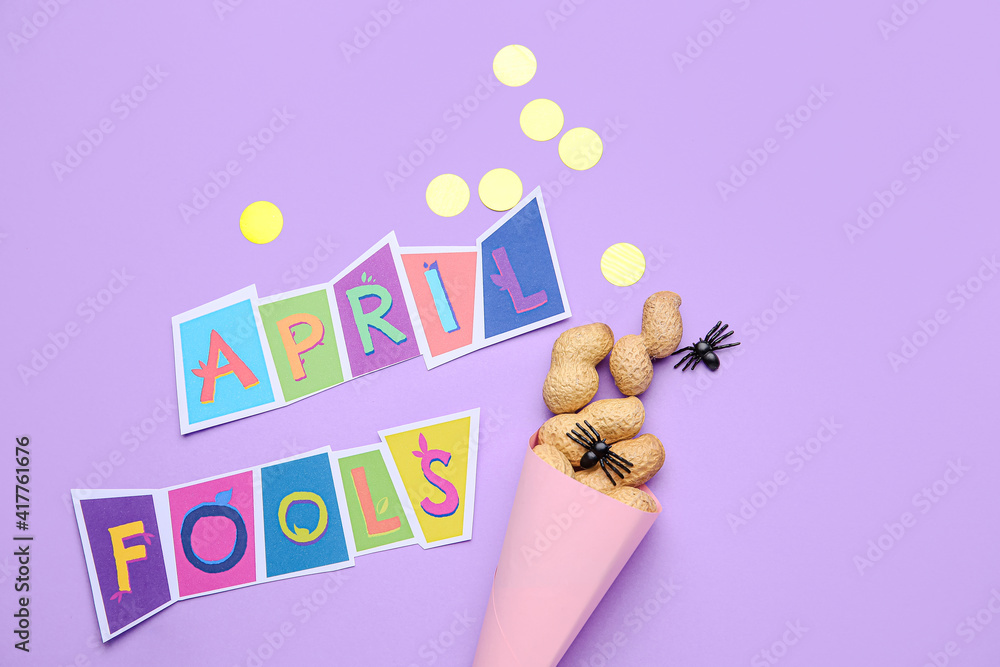 Paper cone with peanuts and fake spiders on color background. April ...