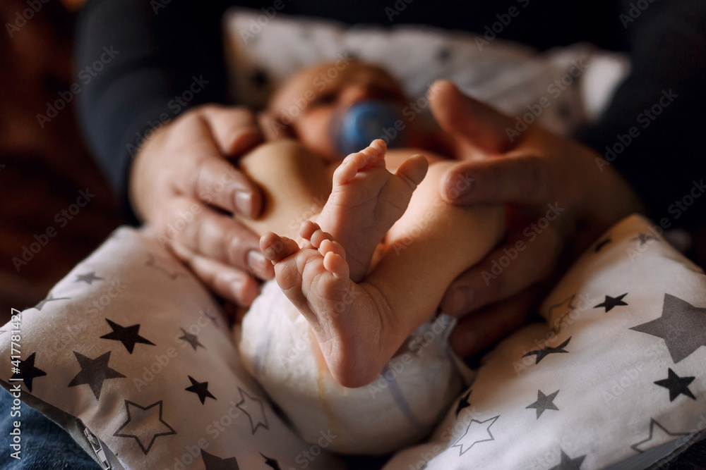Feet of the newborn in the palms of the dad. Little baby fingers and ...