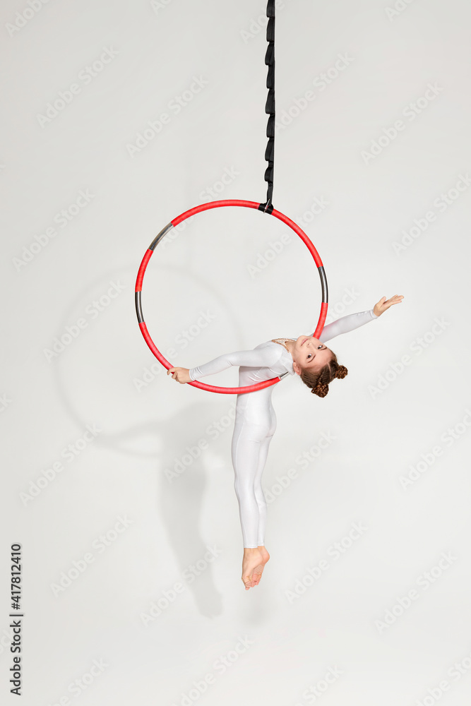 cute child girl gymnast in white sportwear shows an acrobatic ...