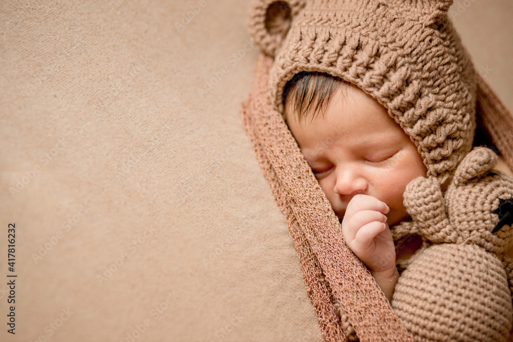 Newborn baby, 10 days old, sleeping in a cosy bear outfit and in a ...