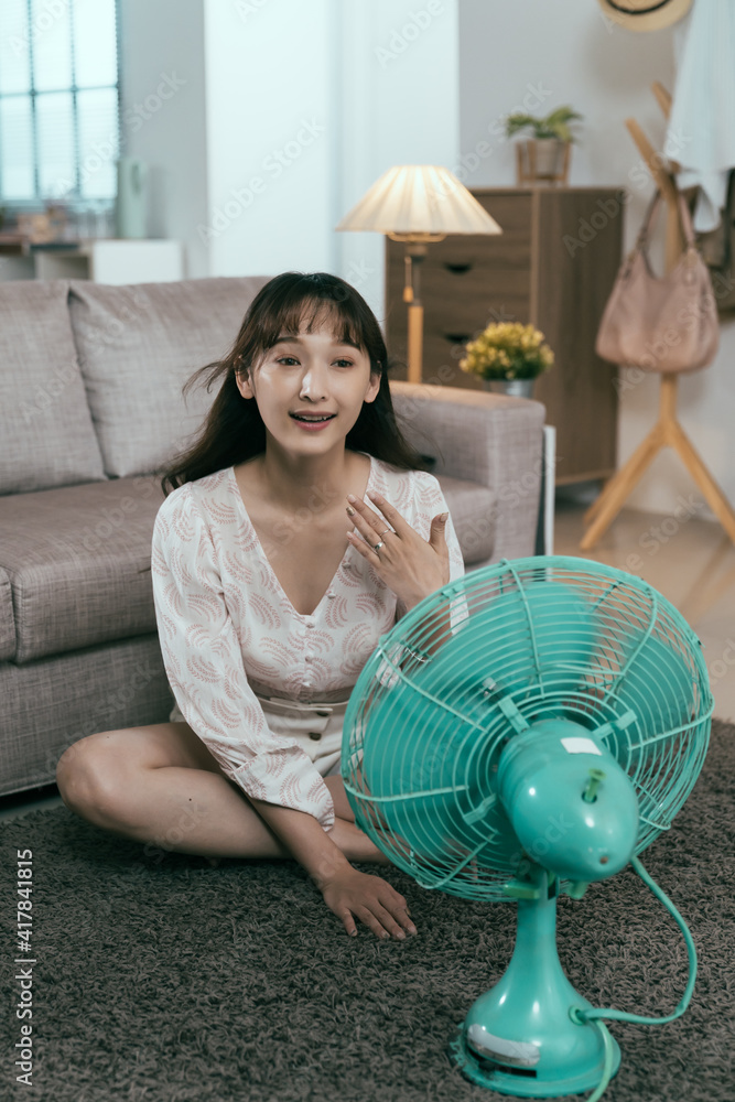 vertical shot asian female sitting behind retro desk fan waving hand ...