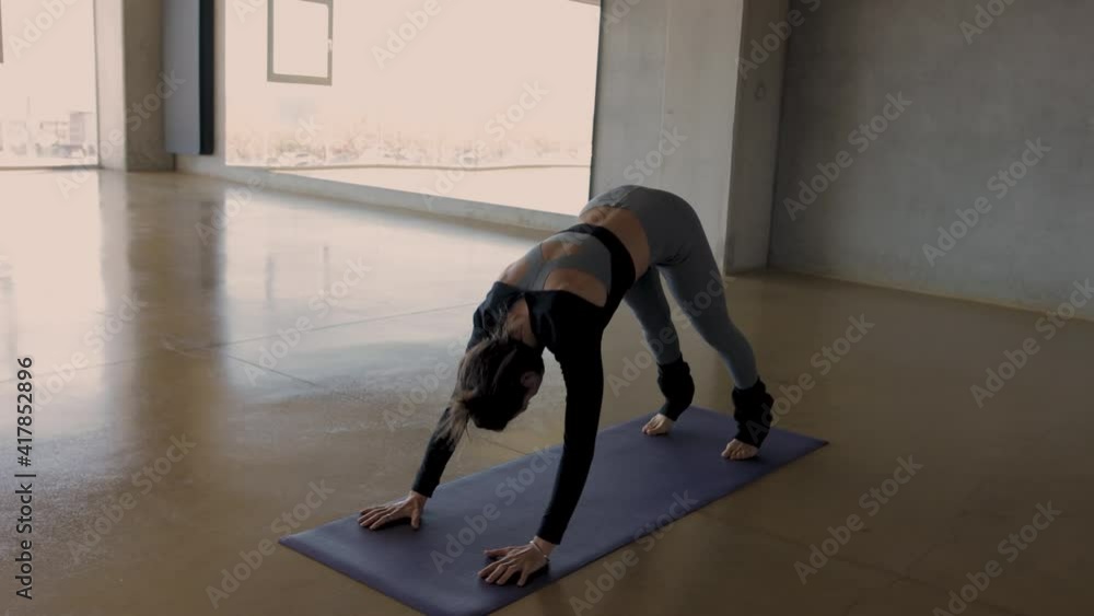 Flexible woman practice yoga postures and doing stretching in loft ...