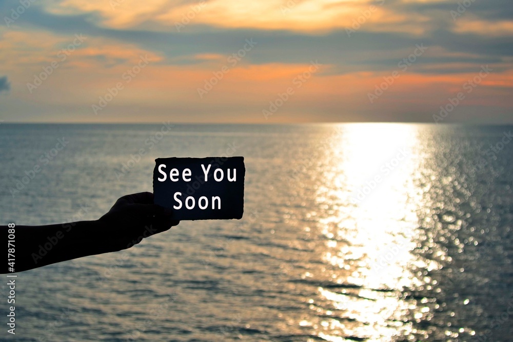 See you soon text on hand holding torn paper with blurred background of ...