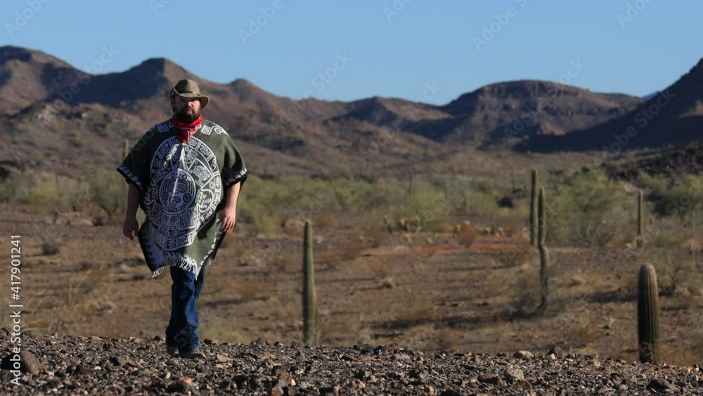 In the Sonoran desert, a desperado man wearing a poncho, red bandanna ...