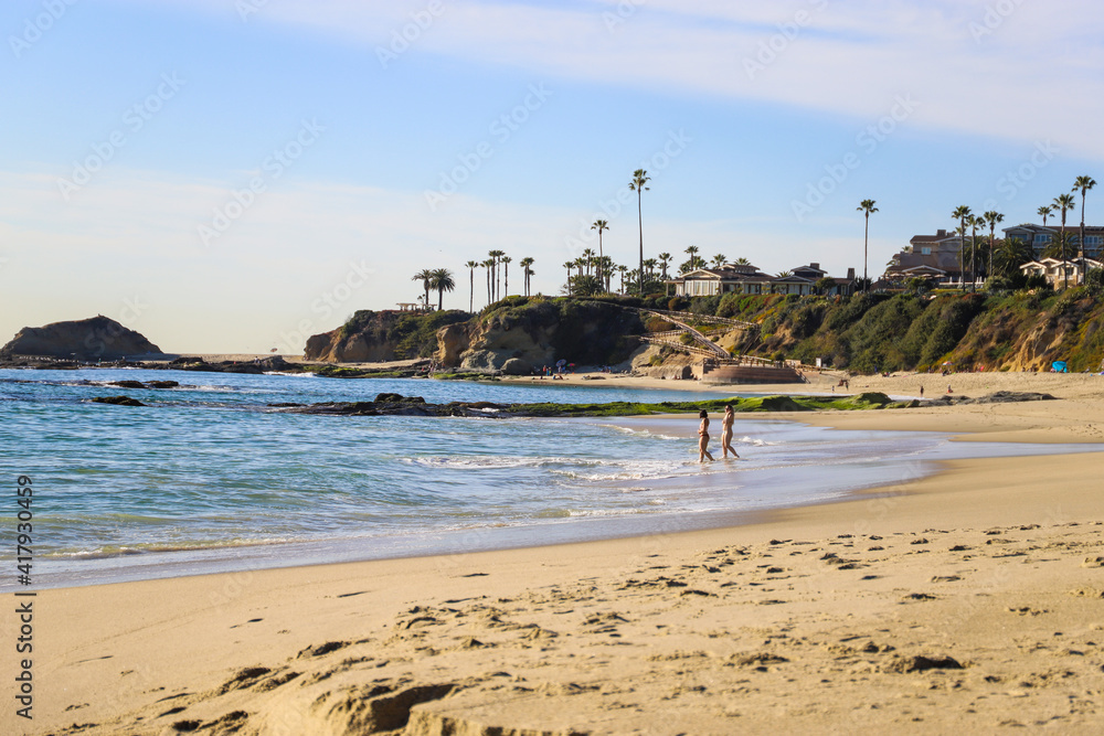 two girls in bathing suits on the beach with vast blue ocean water and ...