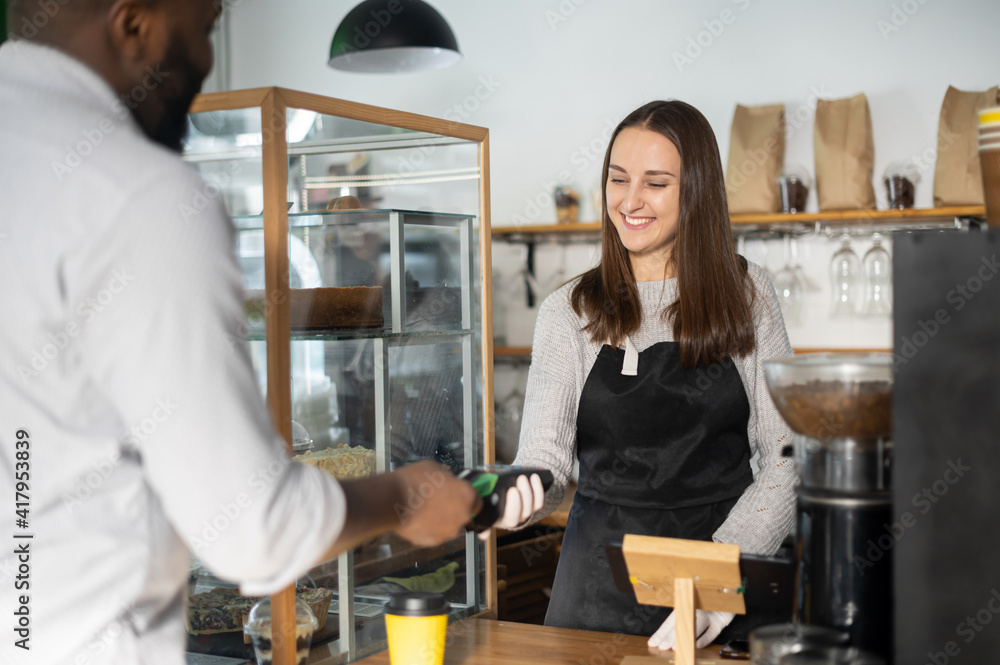 Smiling waitress giving pos payment terminal to african-american ...