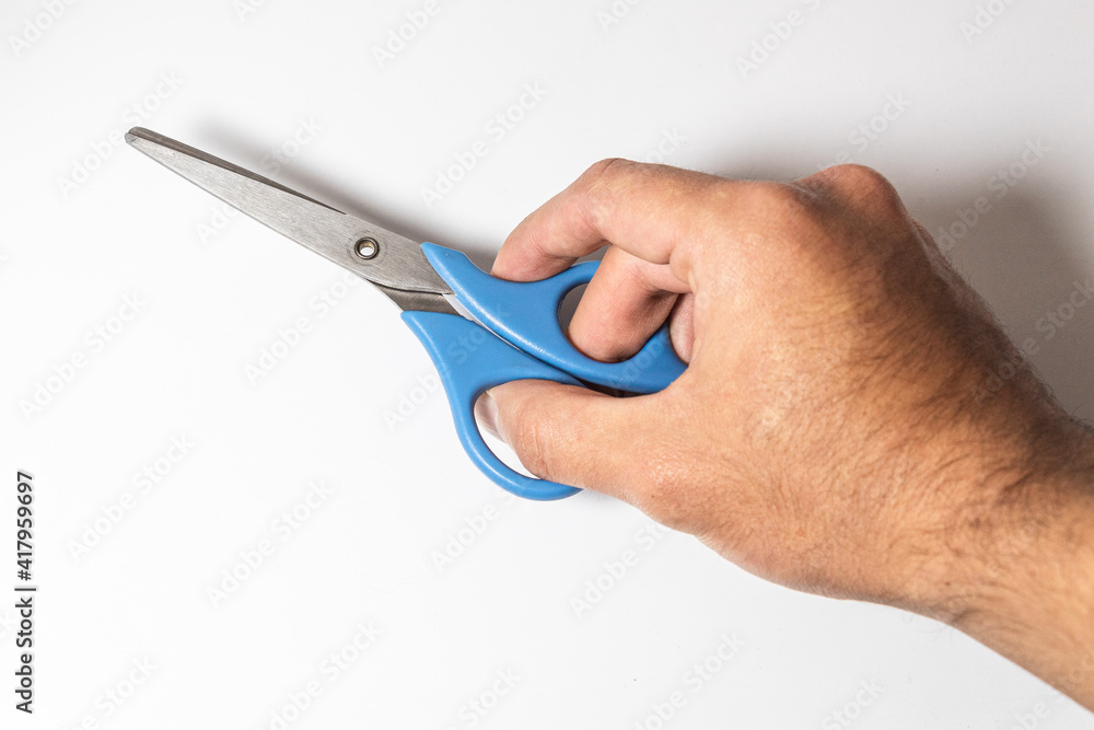 Hand holding blue metal scissors laying over a white background Stock ...