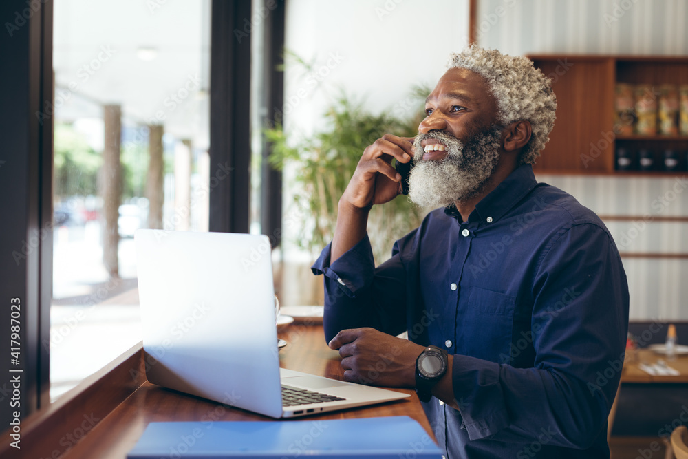 African American Senior Man Sitting At Table In Cafe Using Laptop