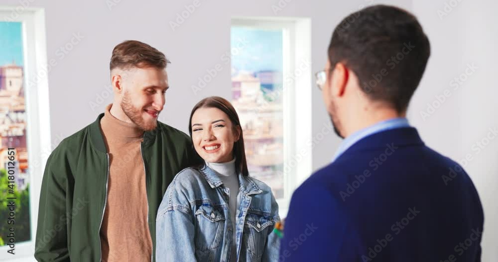 Housing agent is giving keys to buyers of new apartment, happy husband ...