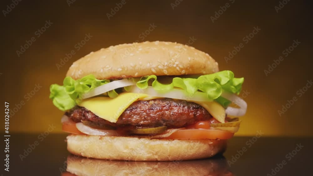 Yummy juicy beef burger with fresh ingredients rotating on mirror table ...