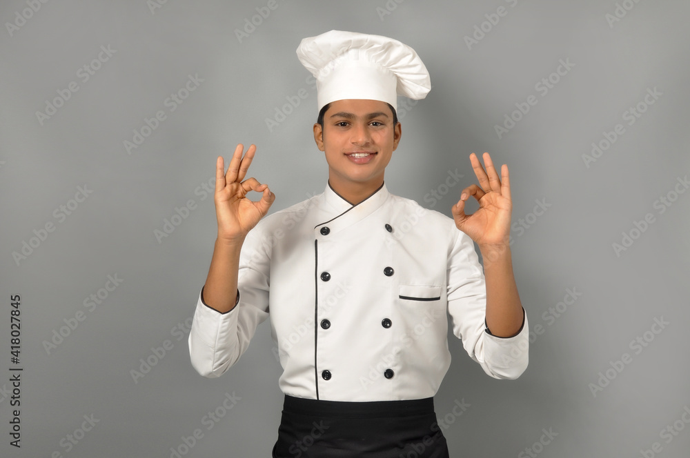 Happy male Indian chef showing ok gesture with one hand over grey ...