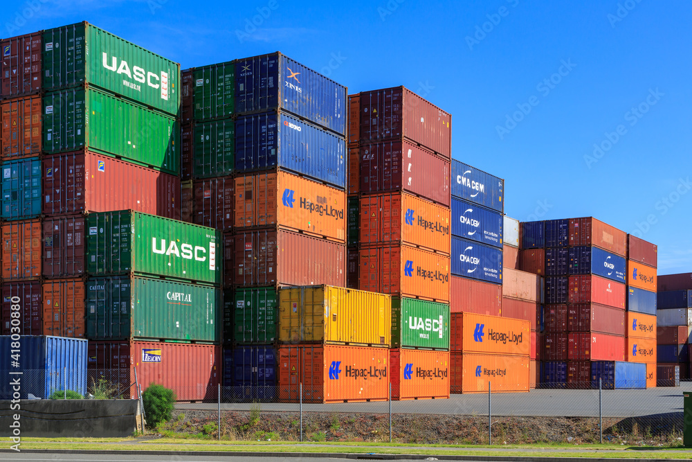 Stacks of colorful shipping containers with various company logos in an ...