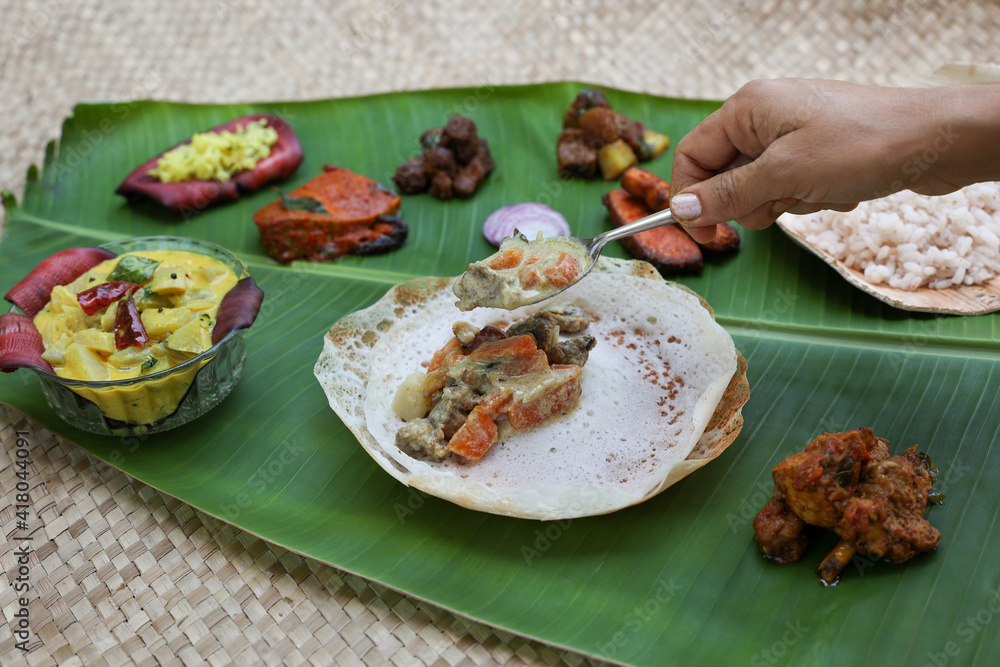 Hand serving mutton stew on Appam Non-vegetarian sadhya Indian food for ...