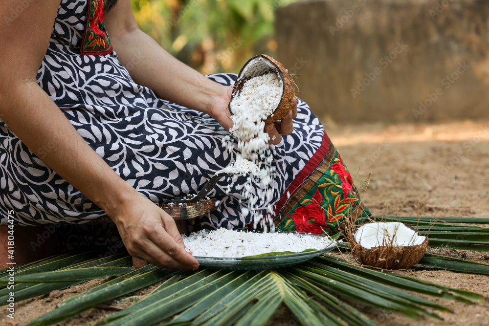 Foto de Woman hand taking fresh grated coconut to prepare homemade ...