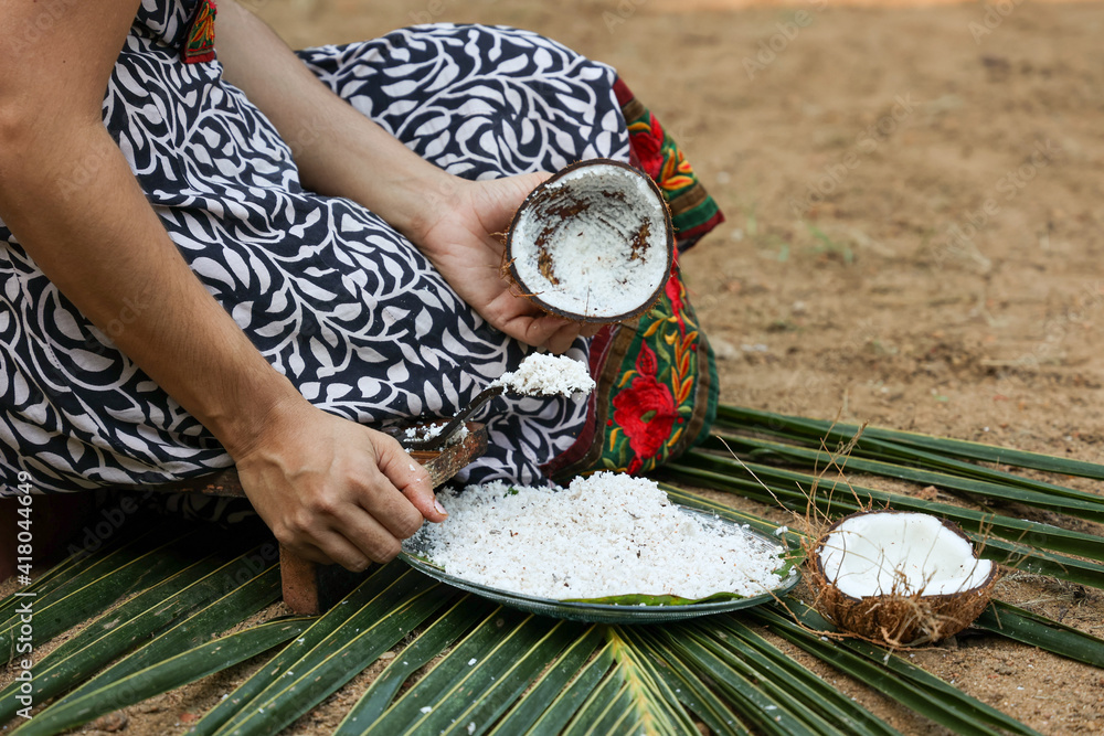 Woman hand taking fresh grated coconut to prepare homemade thick ...