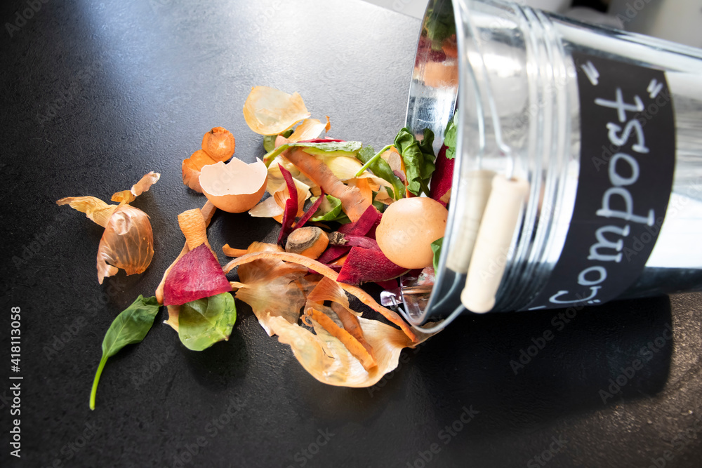 Metal bucket for composting with residue vegetables on black background ...