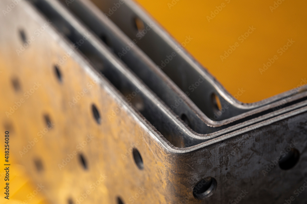 Stack of construction perforated steel angle brackets close up. Low ...