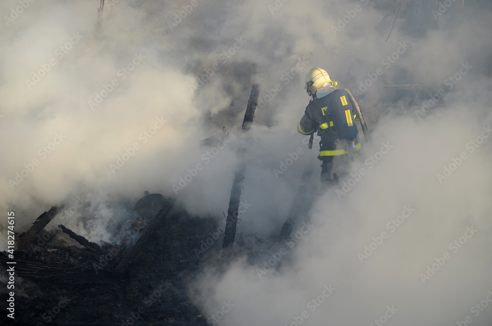 Firefighter with a breathing apparatus shrouded and surrounded by thick ...