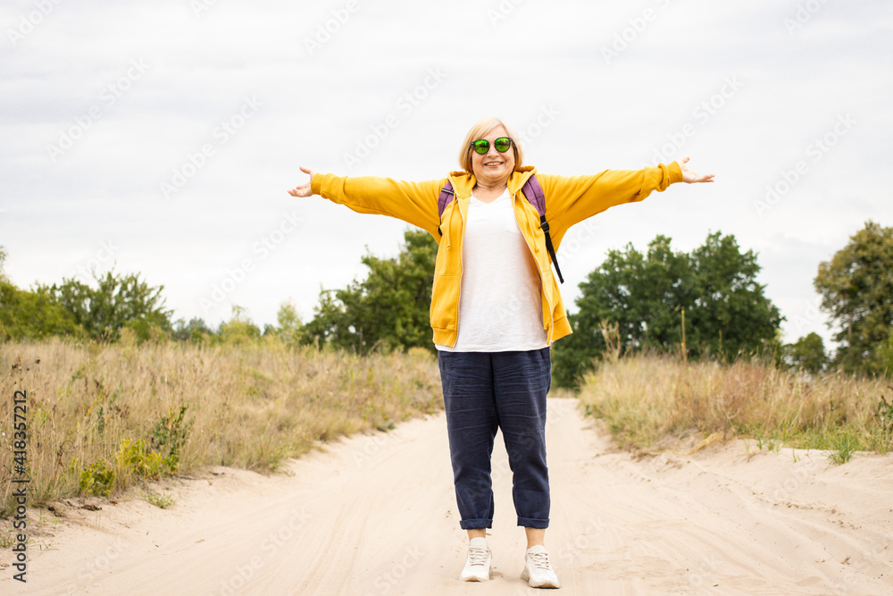 Free happy senior woman in sunglasses and yellow hoodie with arms ...