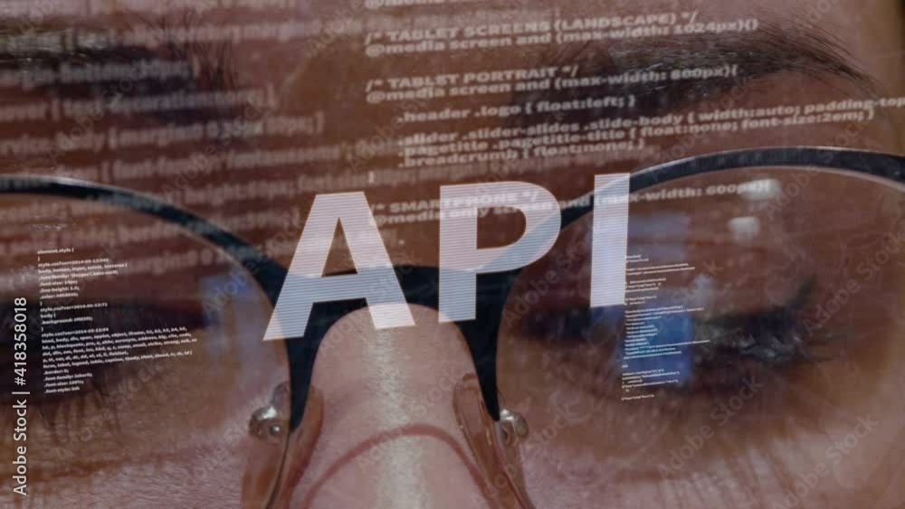 API text on the background of female software developer. Eyes of woman with glasses are looking ...