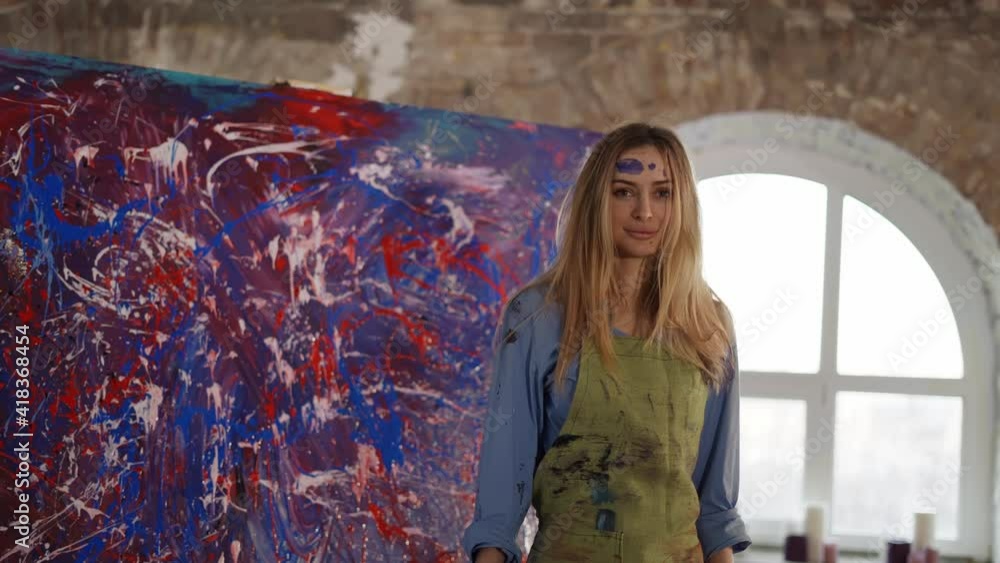 Portrait female painter after finishing her masterpiece in art studio ...