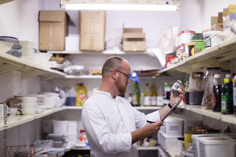 Chef checking stock of goods in storage room Stock Photo | Adobe Stock