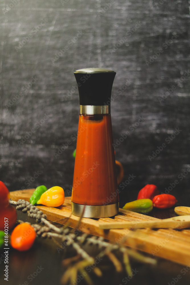 Sesión de fotos para botella de salsa roja picante junto a pimentones y ...