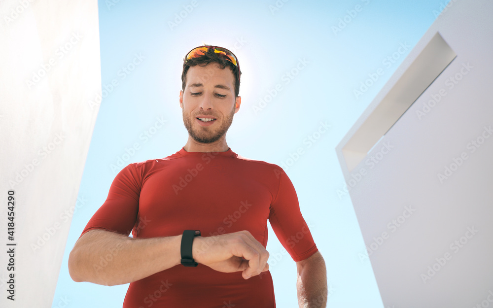Sports watch athlete man running checking his wearable technology ...