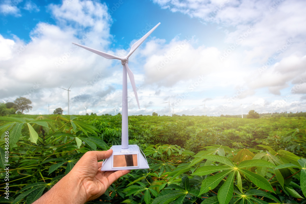 wind turbine in hand with green trees. human hand holding wind turbine ...