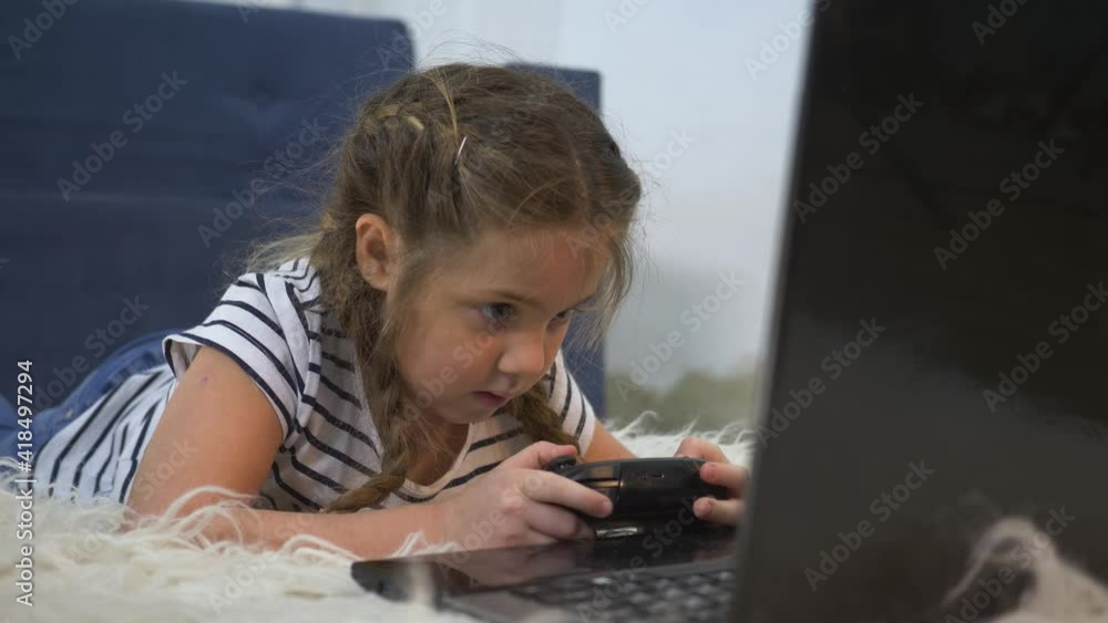 Happy girl playing video games with a joystick. Child gambling ...