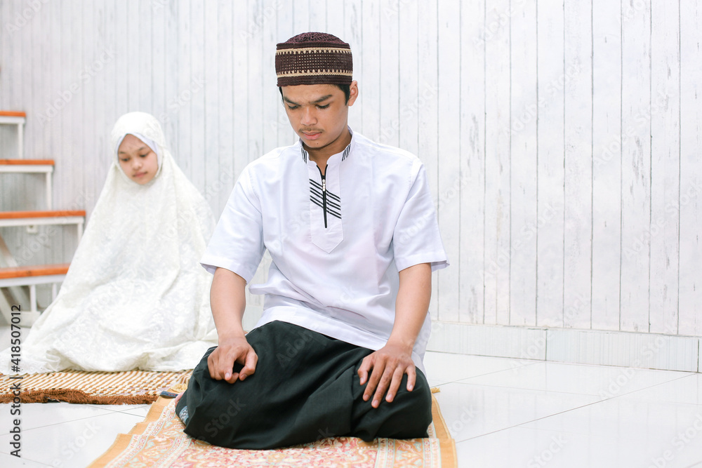 Portrait of young couple muslim doing salat together on the prayer mat ...