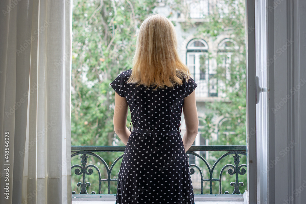 Blonde woman at opened window. Young woman female with blonde long hair ...