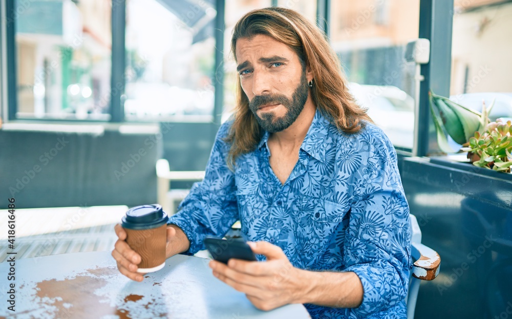Young middle eastern man with sad face using smartphone and drinking ...