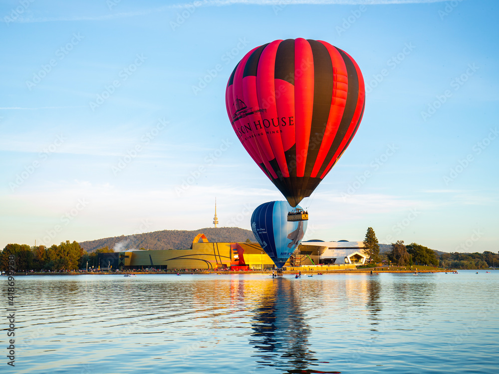 Two hot air balloons floating over Lake Burley Griffin in Canberra ...